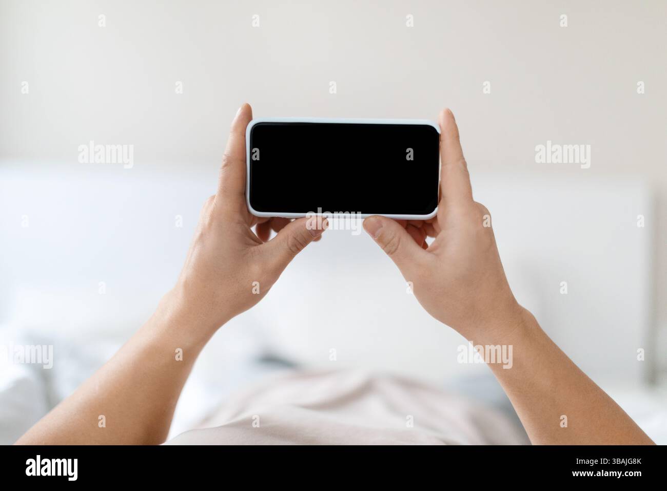 Mobile app concept. Cropped of man lying in bed, holding modern cell ...