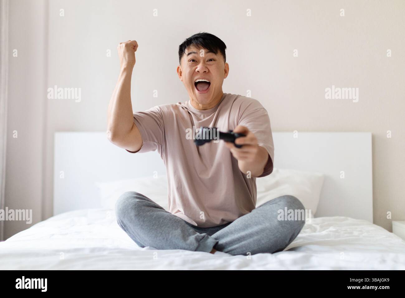Happy positive handsome middle aged asian man gamer having fun at home ...