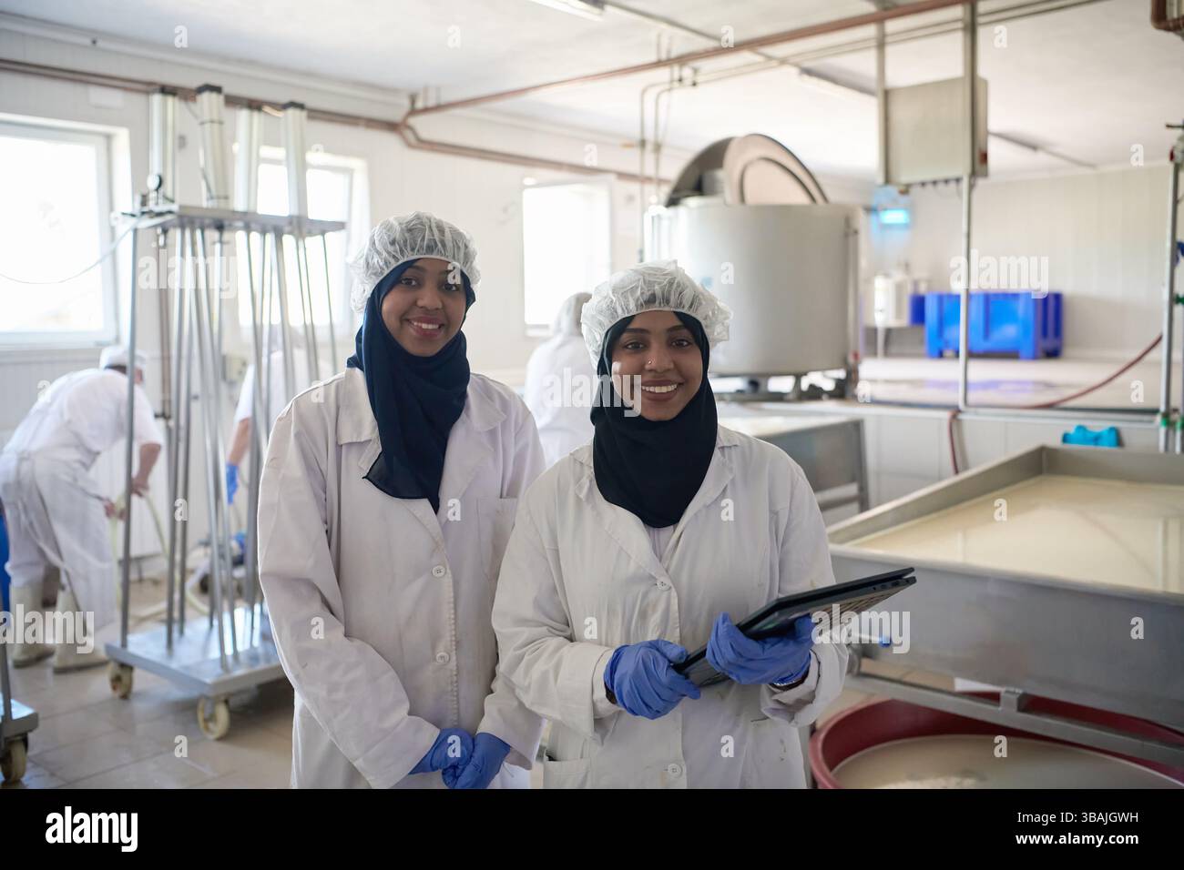 Smiling Middle Eastern female factory workers in hijab and white ...