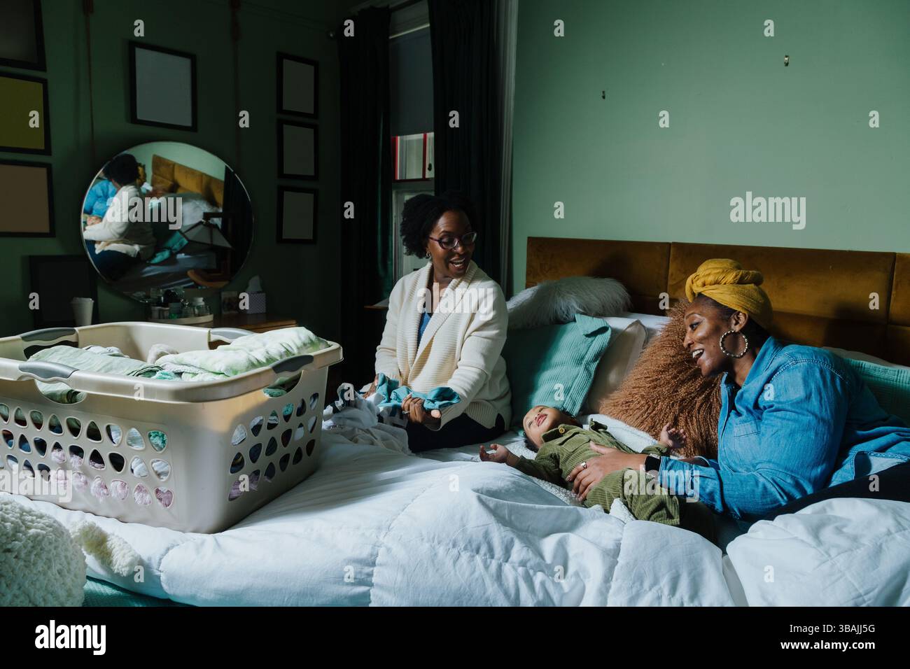 Black aunt folding clothes helping sister with baby while sitting on ...