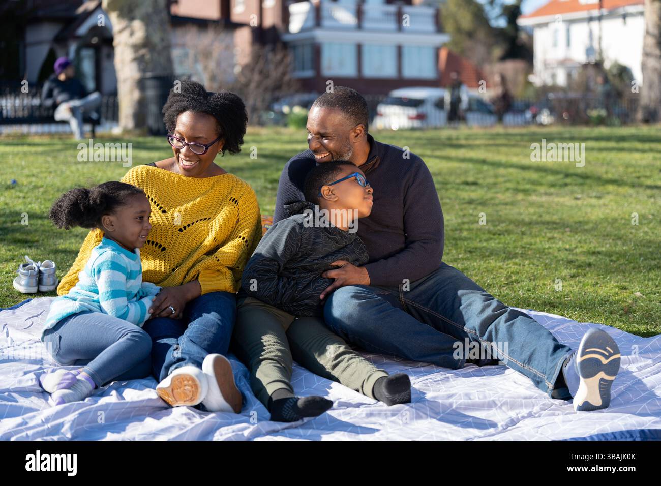 Black family having fun laughing together while sitting on blanket in ...