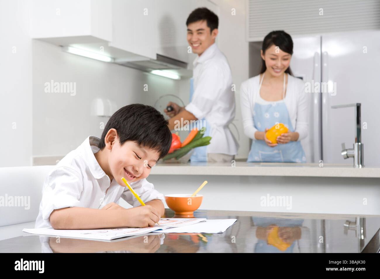 Chinese boy doing homework with parents in kitchen Stock Photo - Alamy