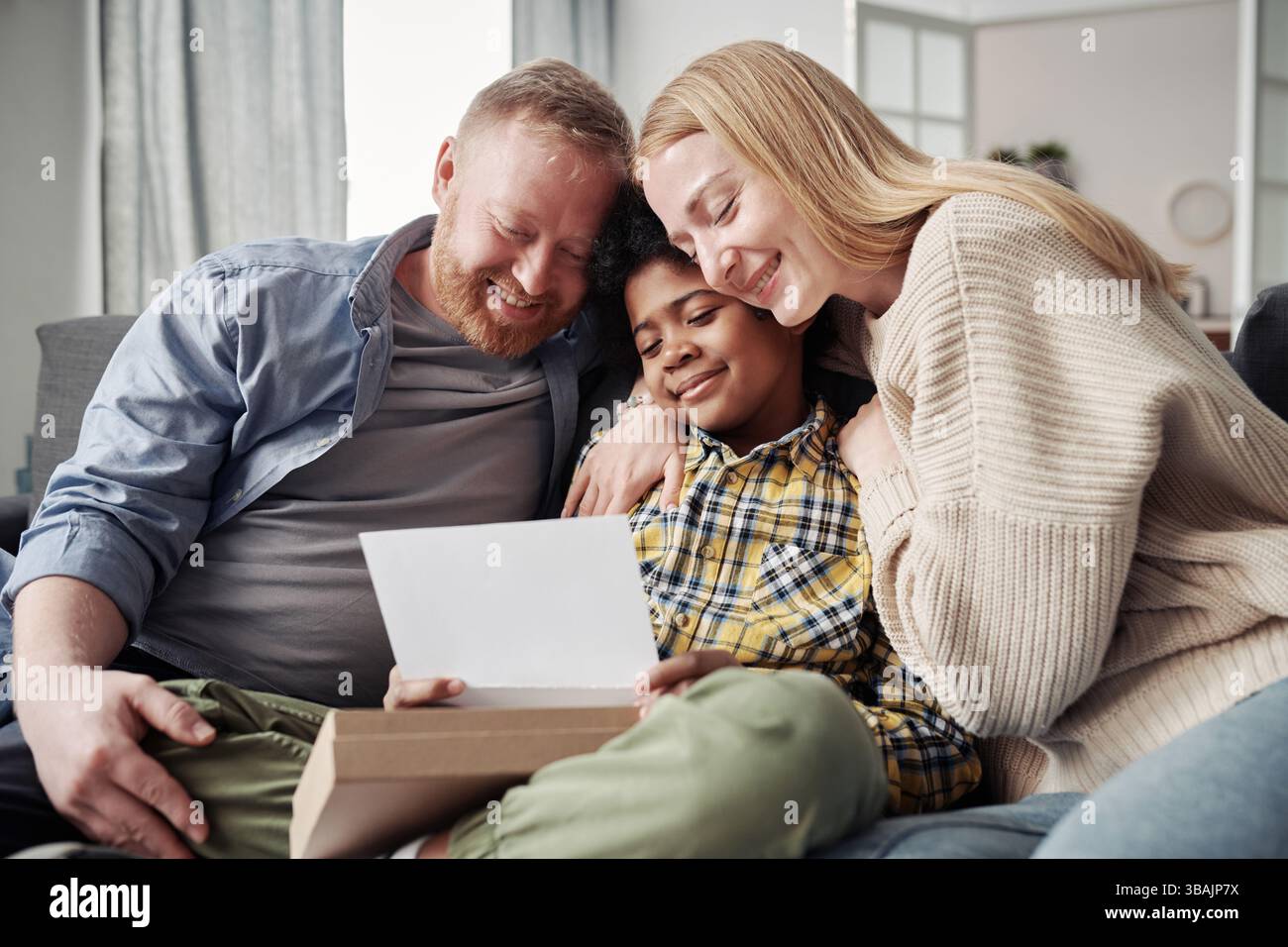 Happy parents embracing their African adoptive son while reading ...