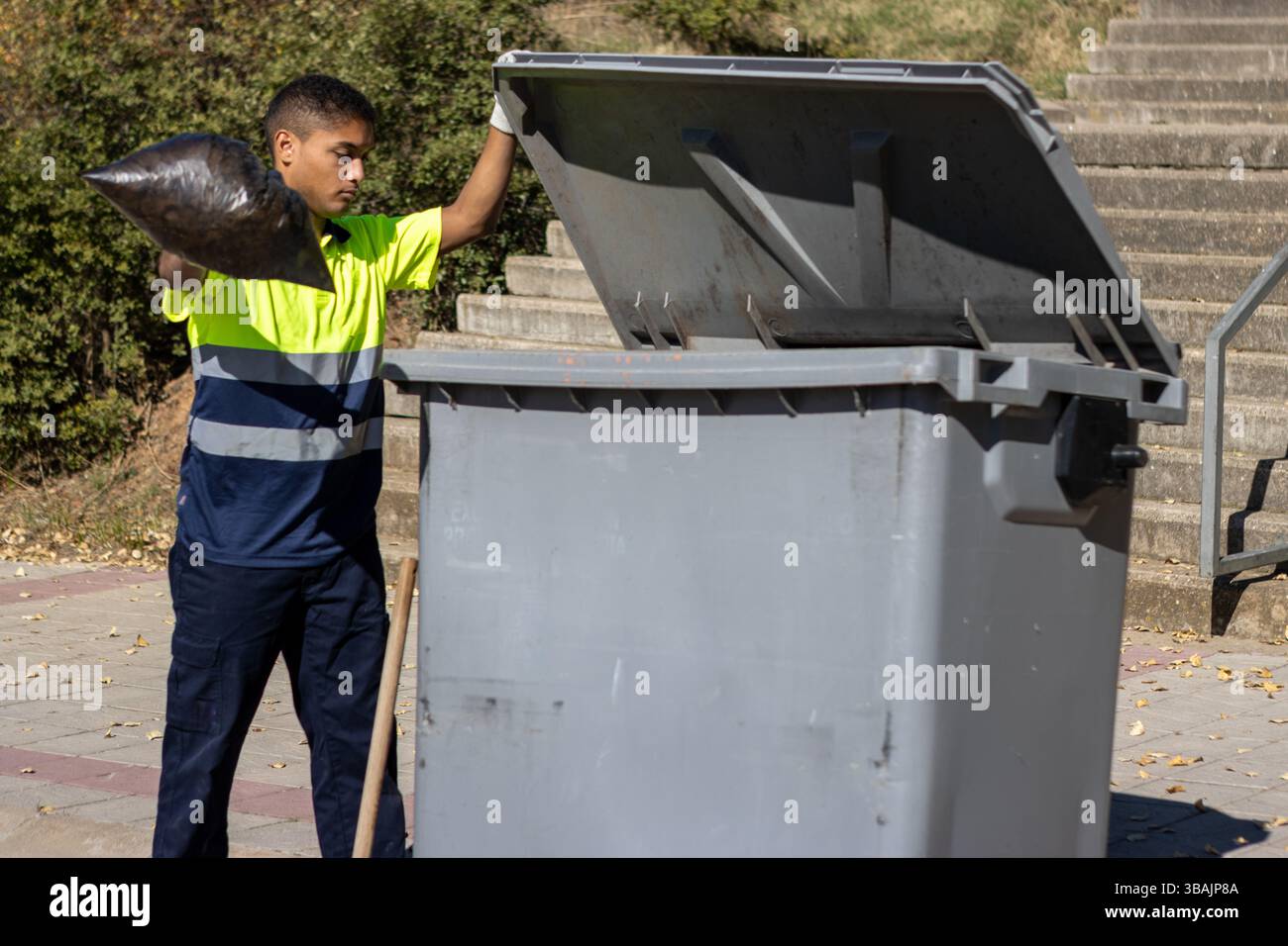 portrait of a latin garbage man throwing a bag of garbage collected ...