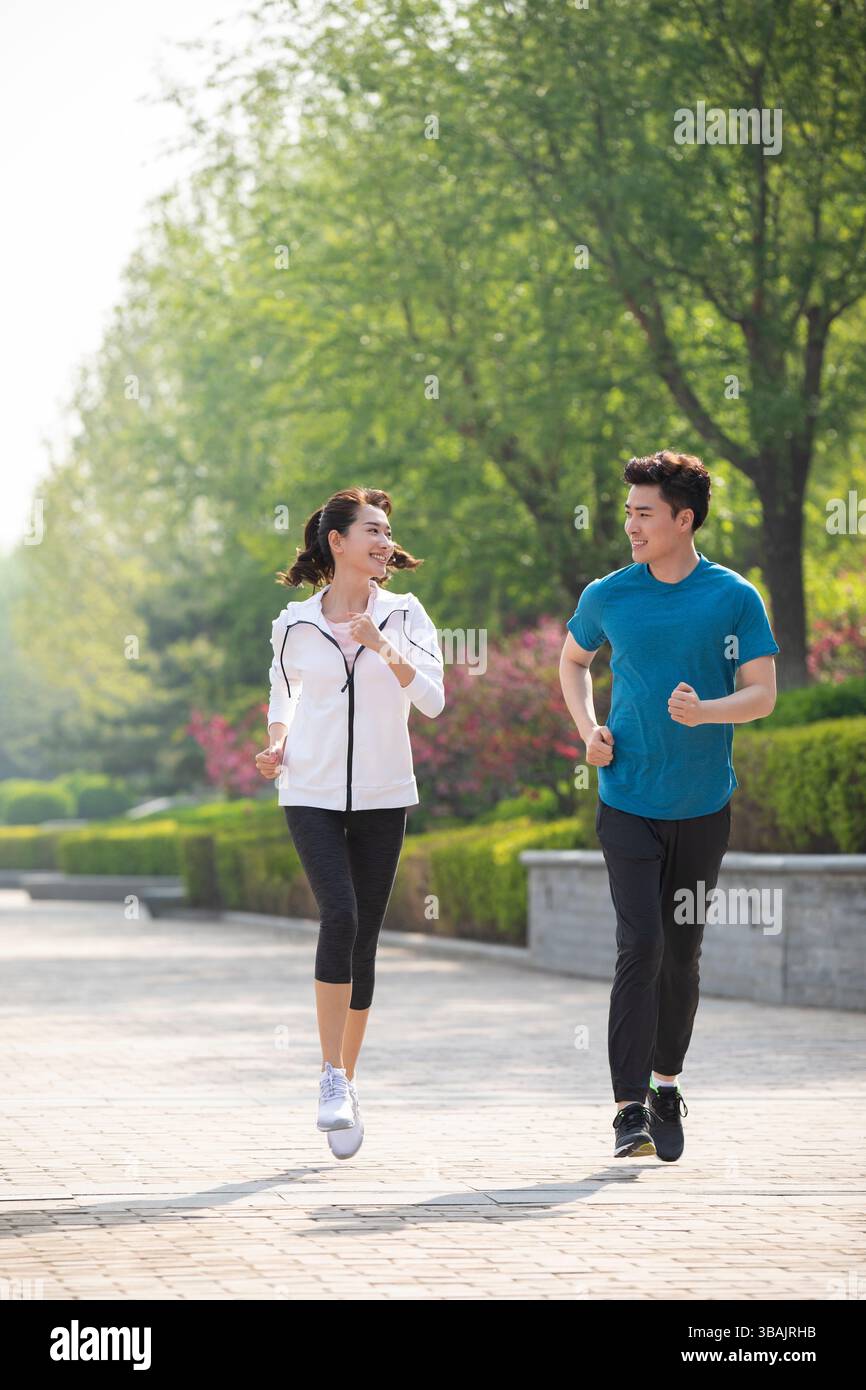 Smiling Chinese couple in fitness wear looking at each other while ...
