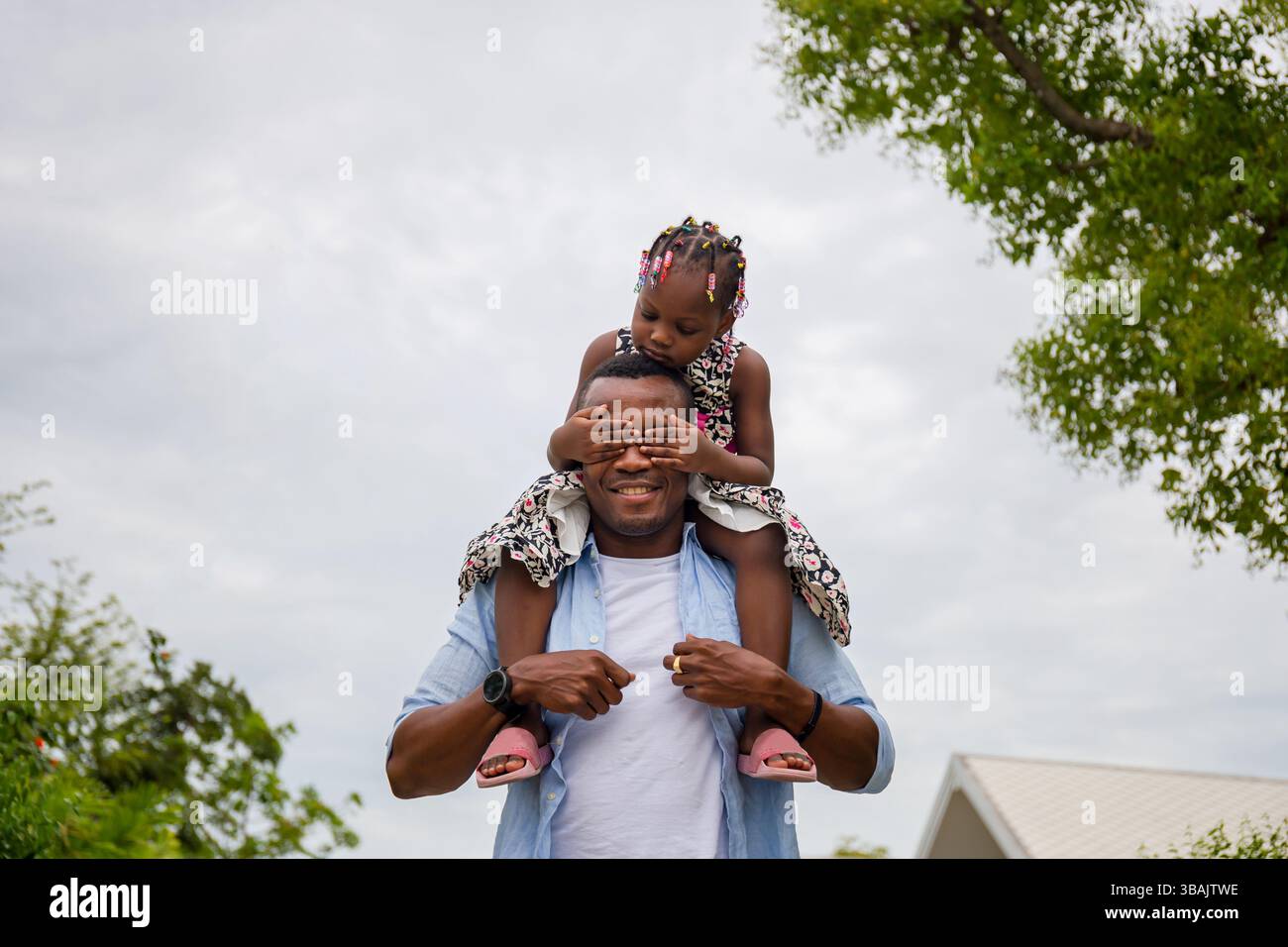 Happy father carrying daughter on shoulders, African american girl on the shoulders of his ...
