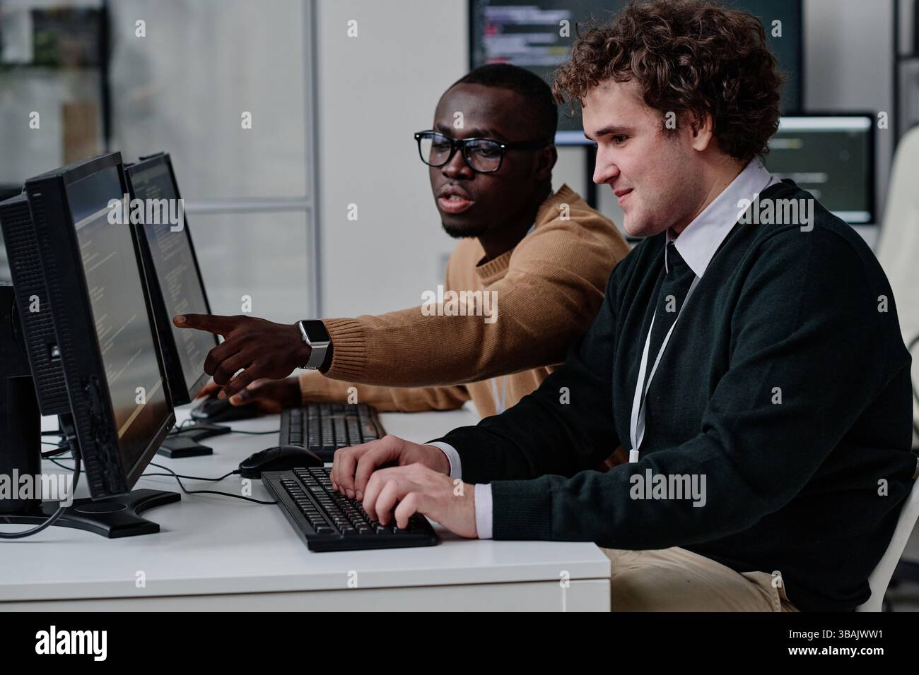 Programmer pointing at computer monitor with codes and talking to his ...