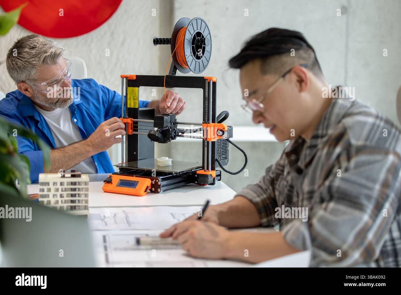 Colleagues architects working with 3D printer and projecting house ...