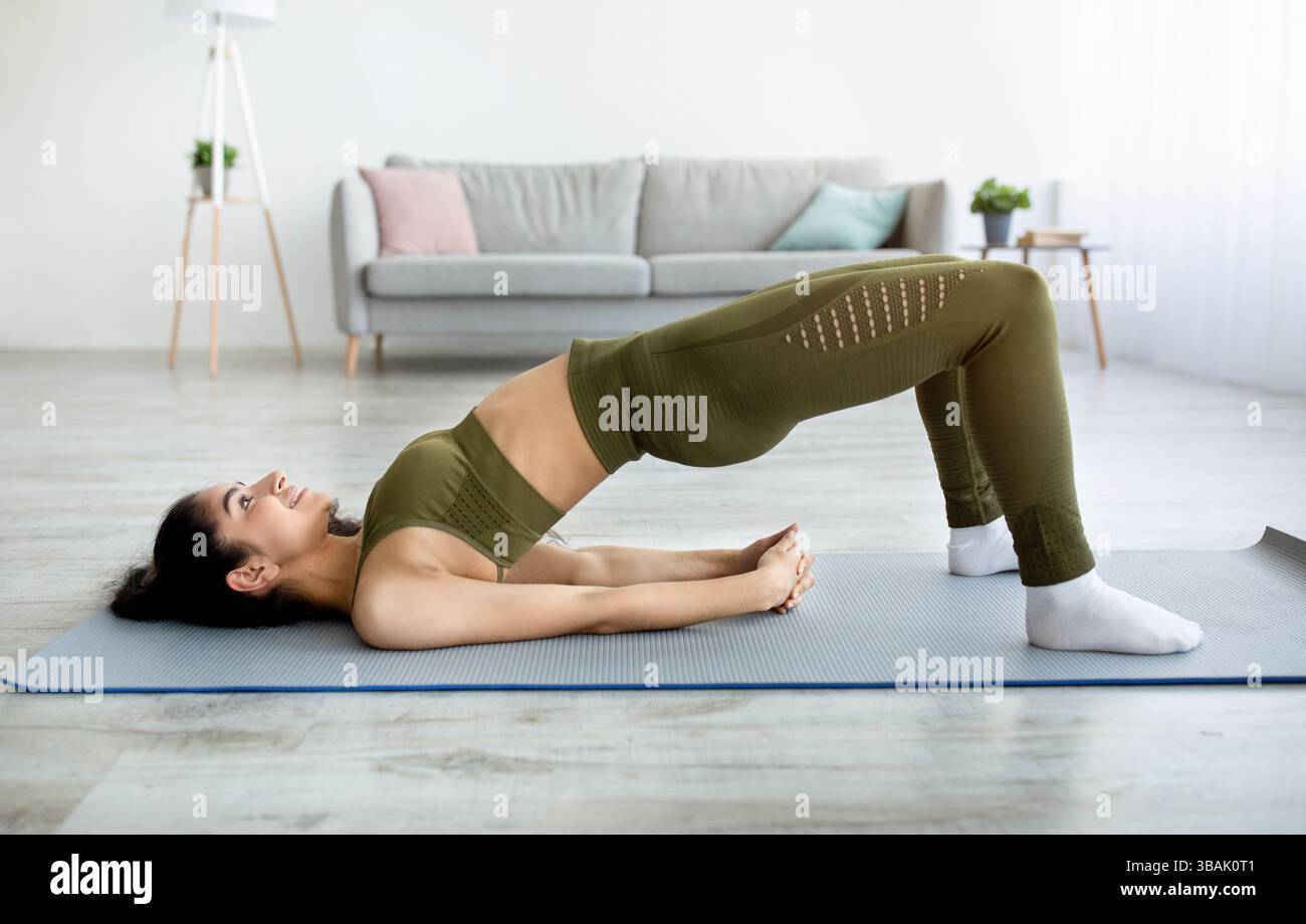 Side view of Indian lady doing abs exercise, standing in half bridge ...