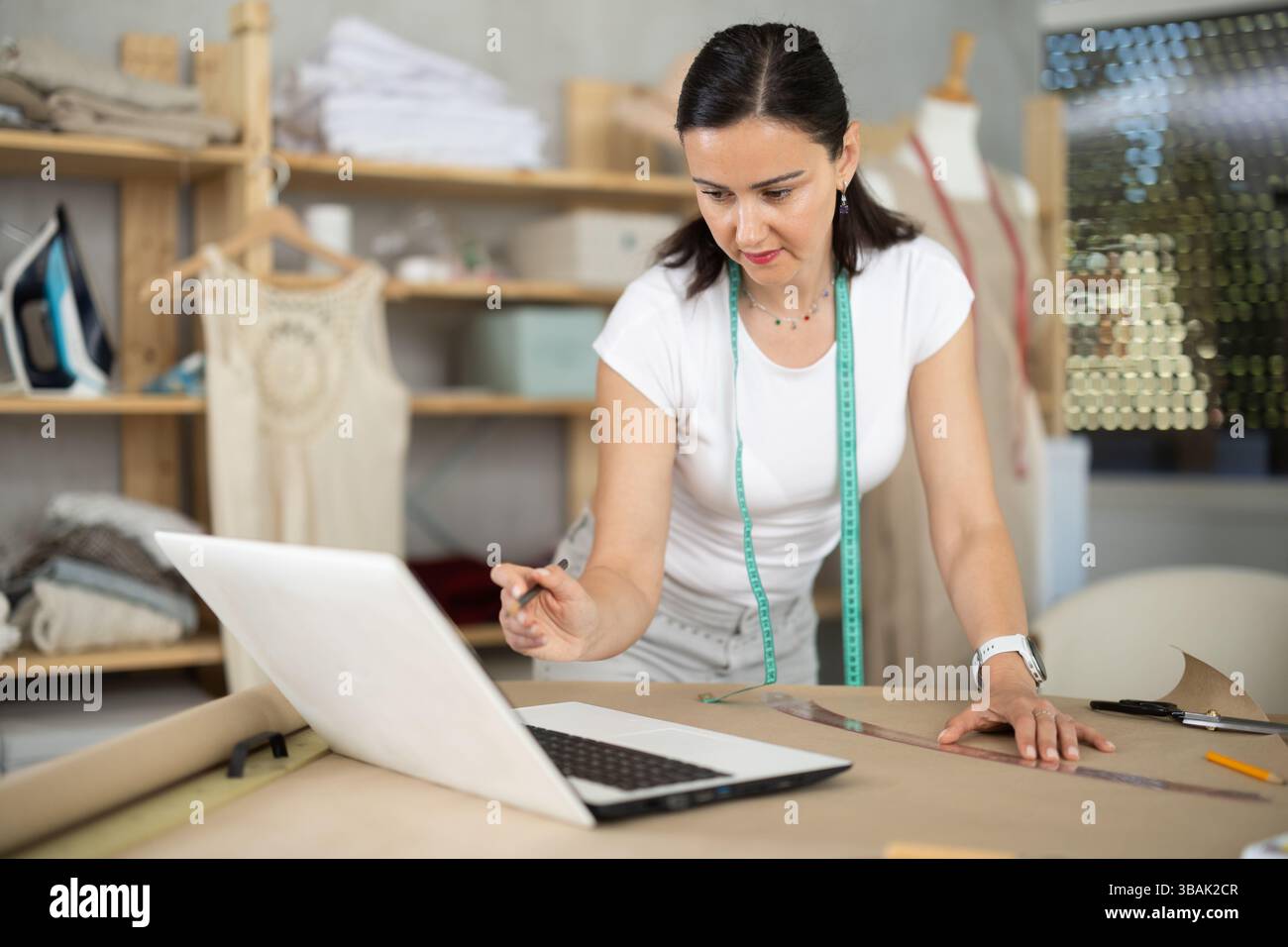 Woman tailor uses computer when creating drawing of future product ...