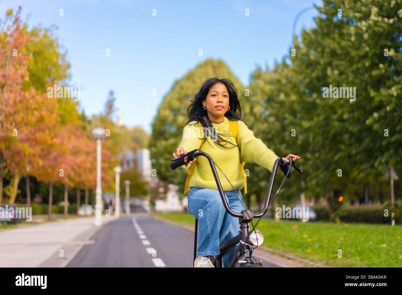 Young asian female student cycling on her way to university campus ...