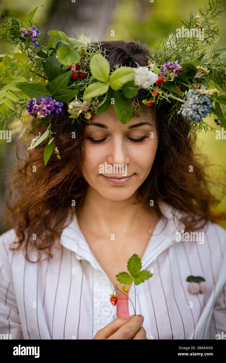 Woman with flower crown holding hands to chest, eyes closed in peaceful nature. Connection to ...
