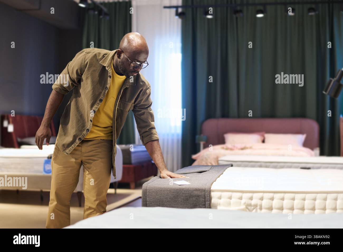 Young male client of furniture shop or store department bending over ...