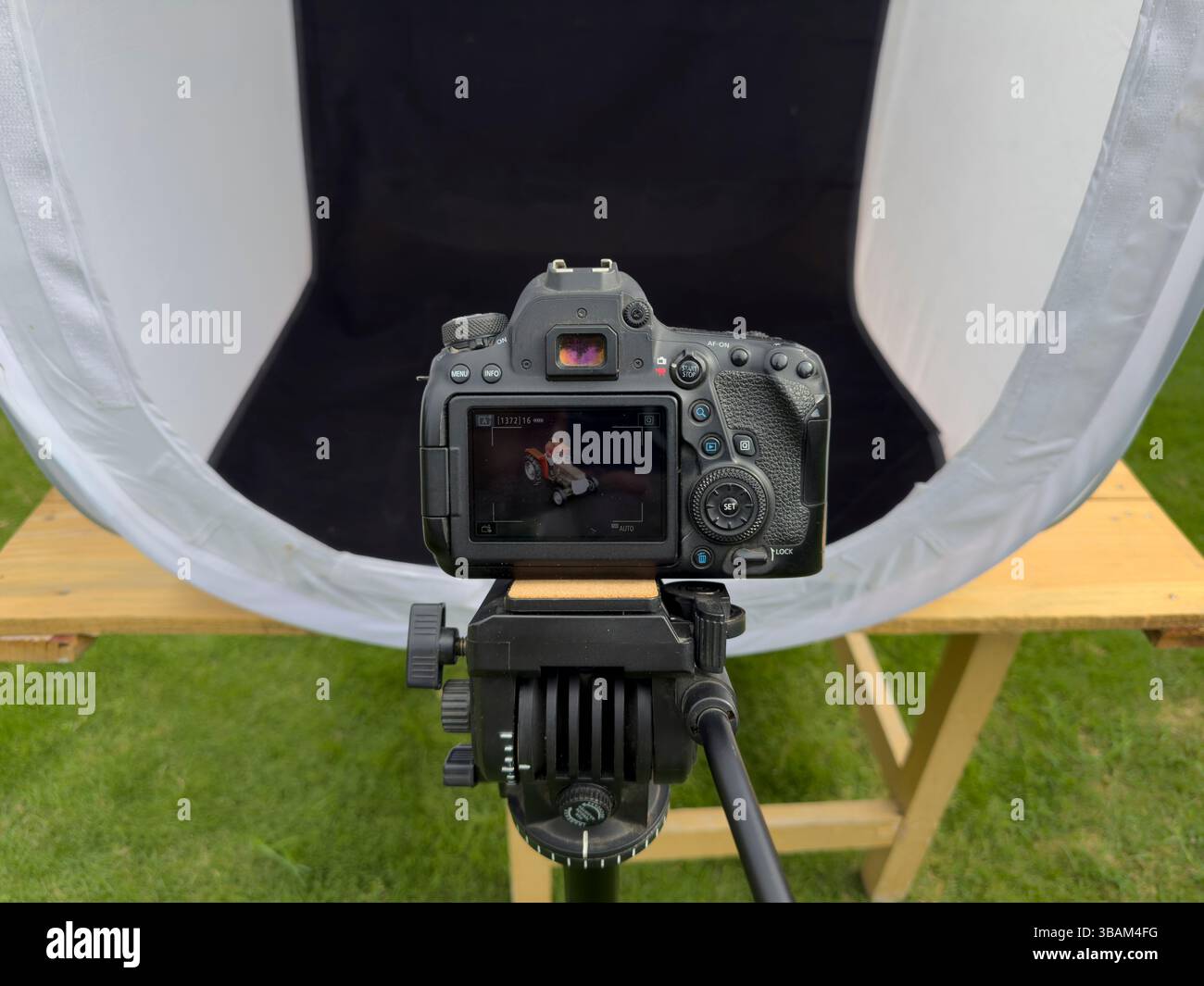 DSLR camera shooting toy tractor in portable light tent studio closeup ...