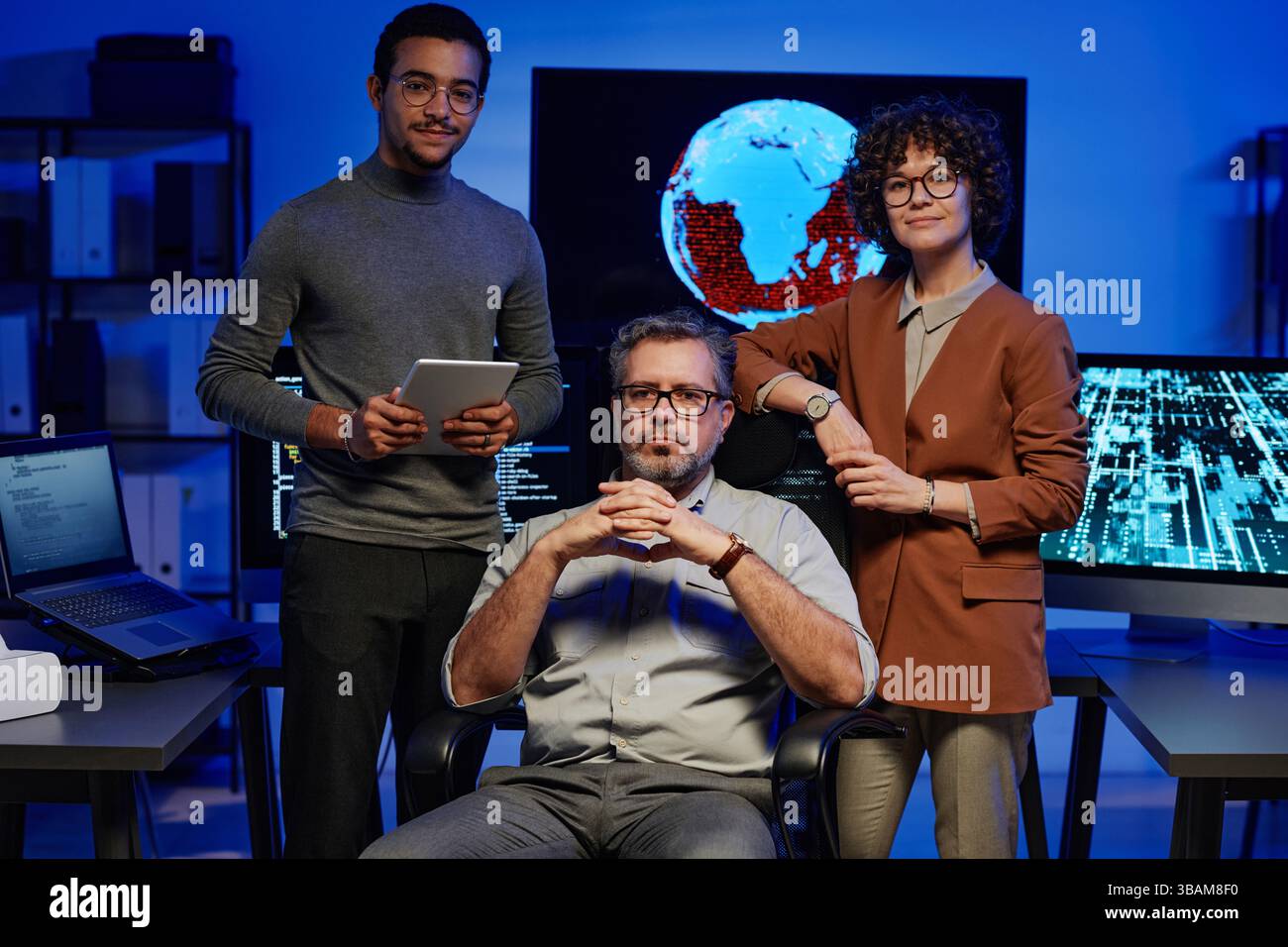 Group of three successful interculltural programmers looking at camera while two young ...