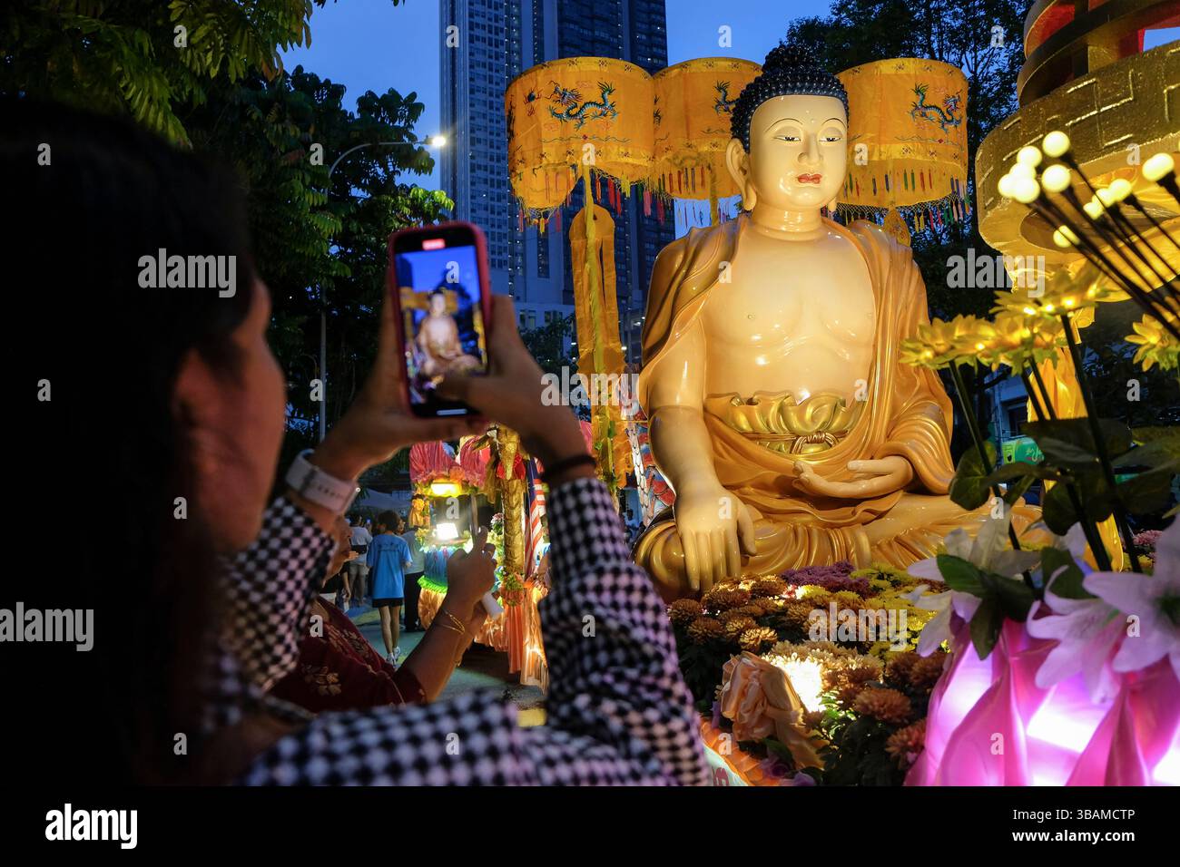 A Buddhist devotee takes photo of a giant golden Buddha statue on a ...