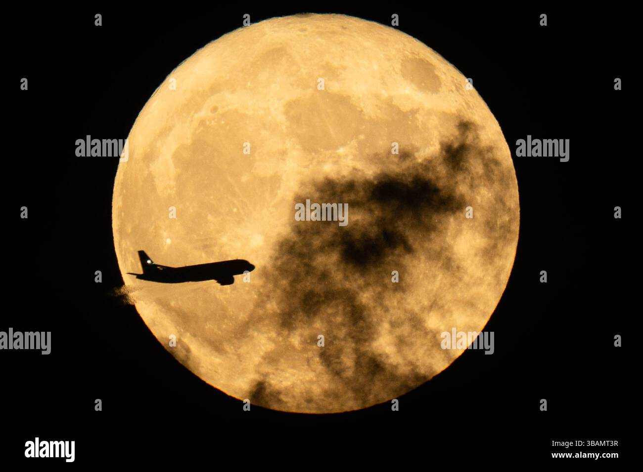 A plane flies in front of the full moon, also known as the Flower Moon ...