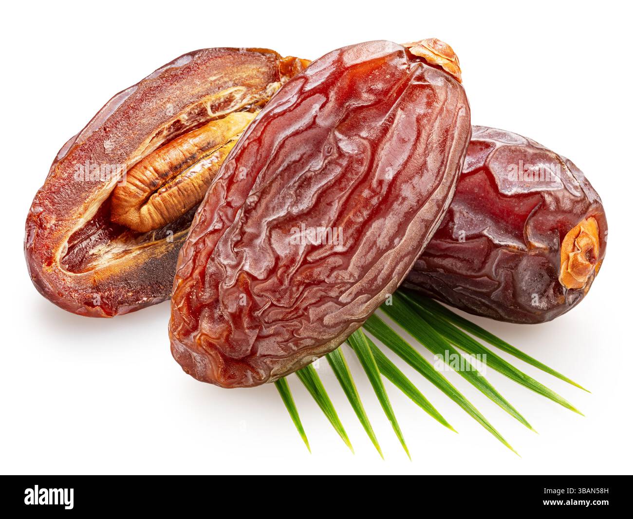 Two semi-dried dates and date fruit cut in half lie on palm leaves ...