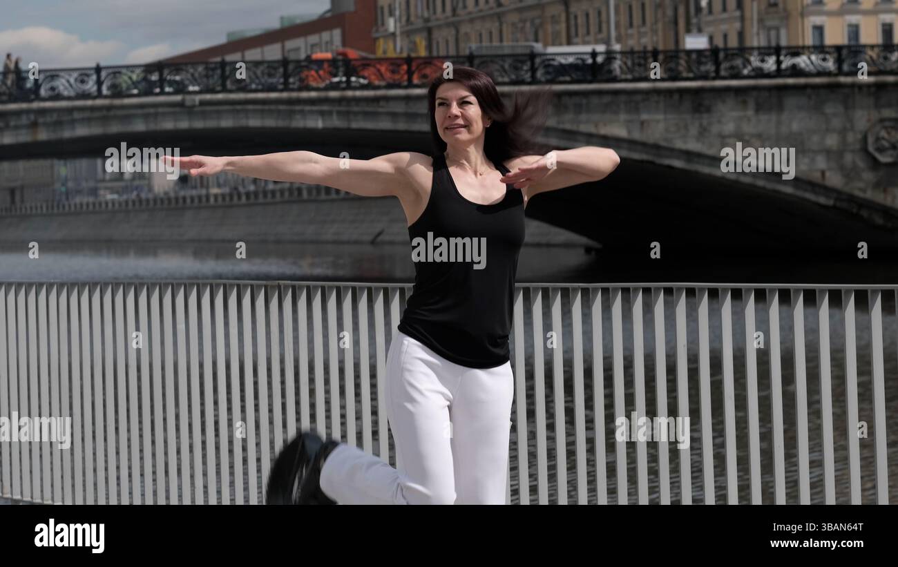 A fit woman performs an expressive movement against a backdrop of ...