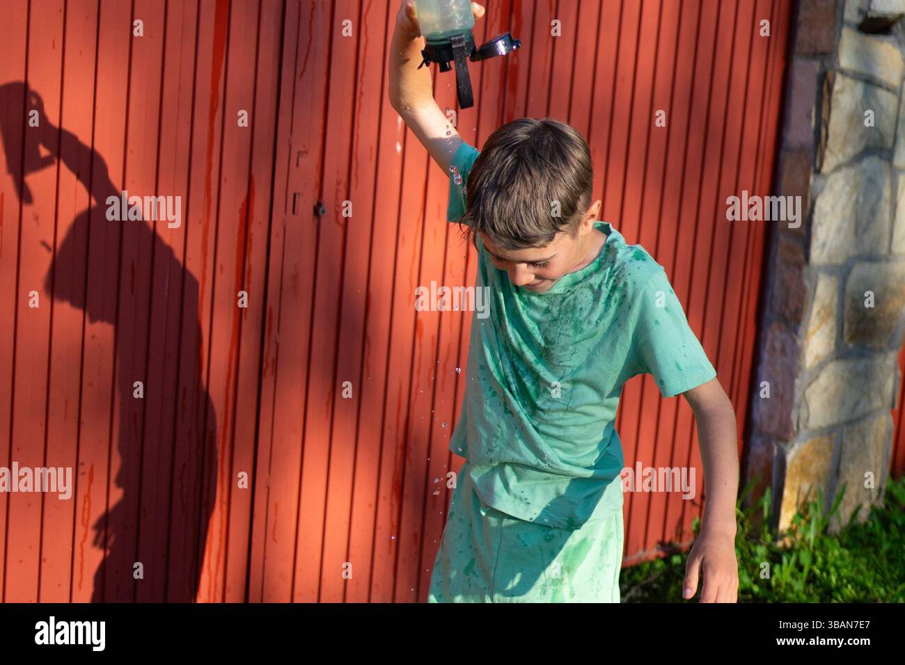 Child cooling off by pouring water on himself from a bottle on a hot ...
