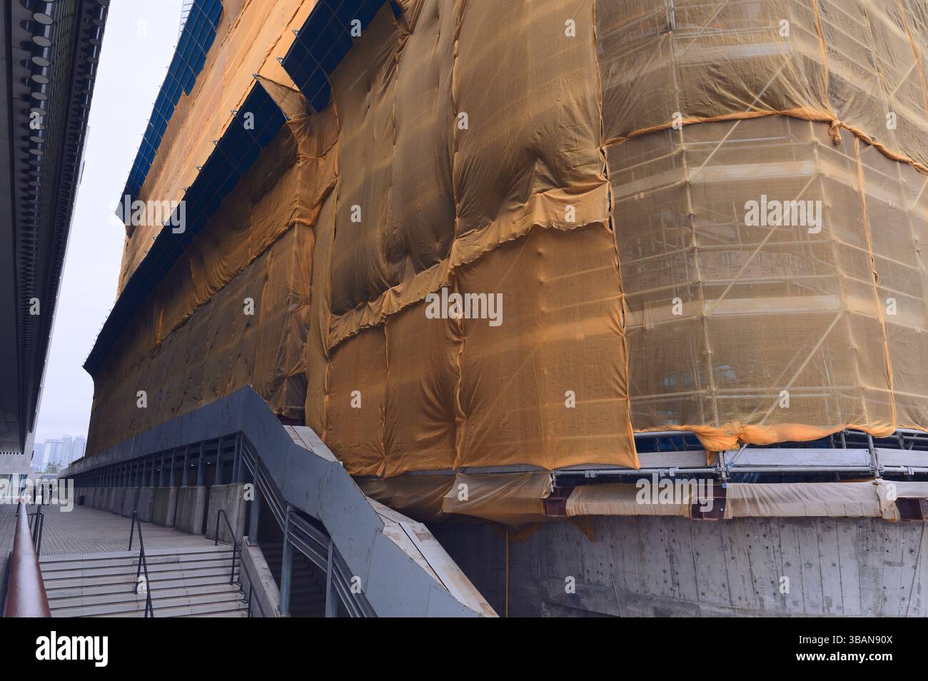 A towering structure under renovation at the M+ museum, wrapped tightly ...