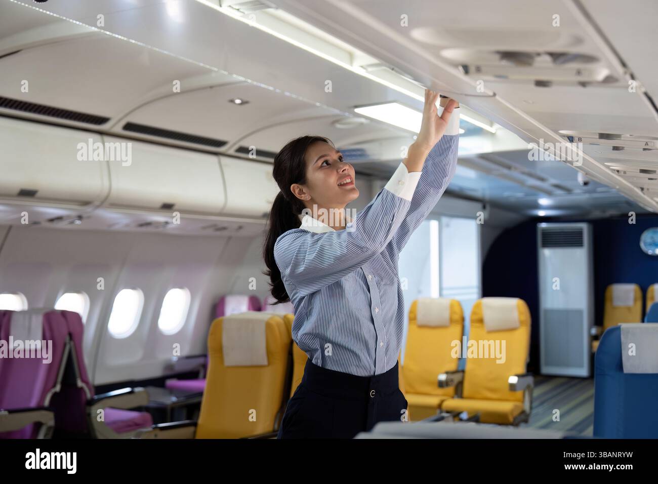 Business travel: Flight attendant adjusting overhead compartment Stock ...