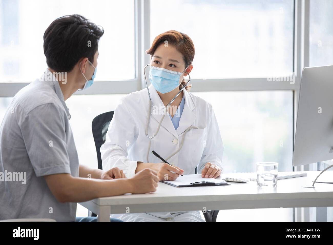 Chinese female doctor wearing surgical mask talking to male patient ...