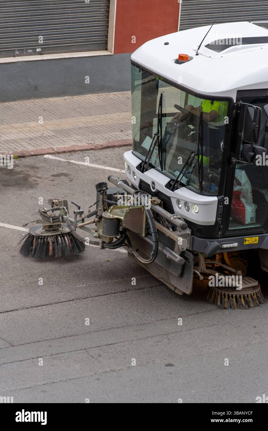 A street sweeper is cleaning the street. The street sweeper is white ...