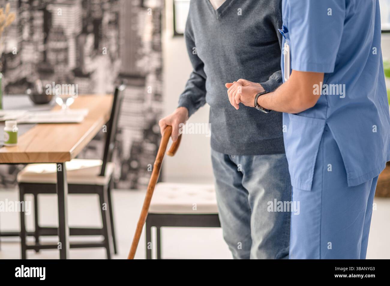 Cropped photo of a nurse in uniform supporting an old man with a ...