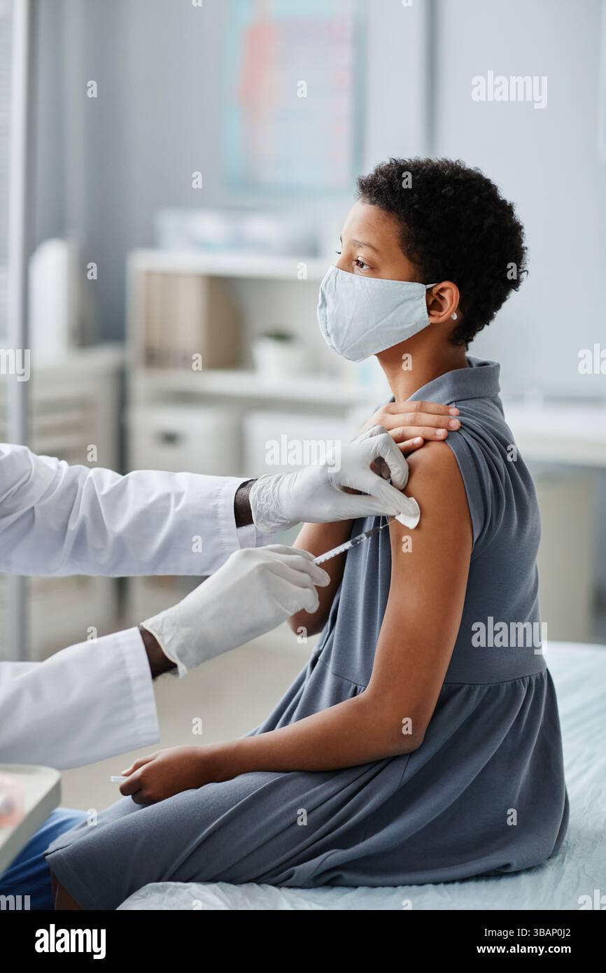 Vertical portrait of African-American girl getting vaccinated in child ...