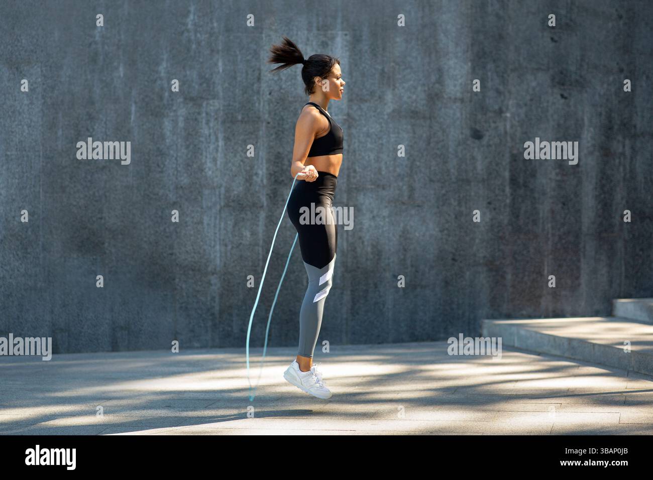 Side view of black woman exercising with skipping rope at park over ...