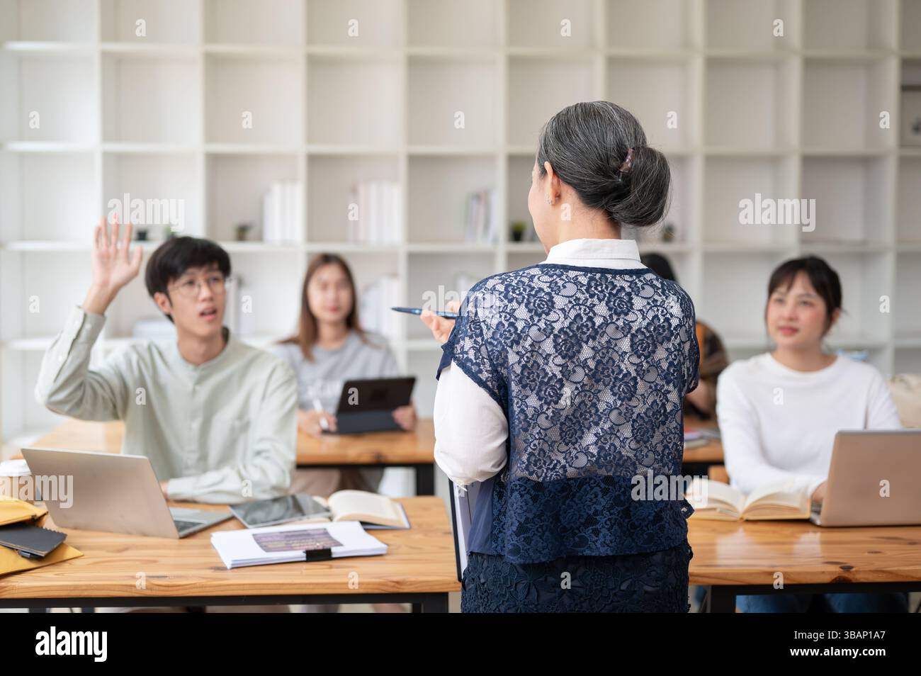 A back view image of a mature Asian female teacher professor giving a ...