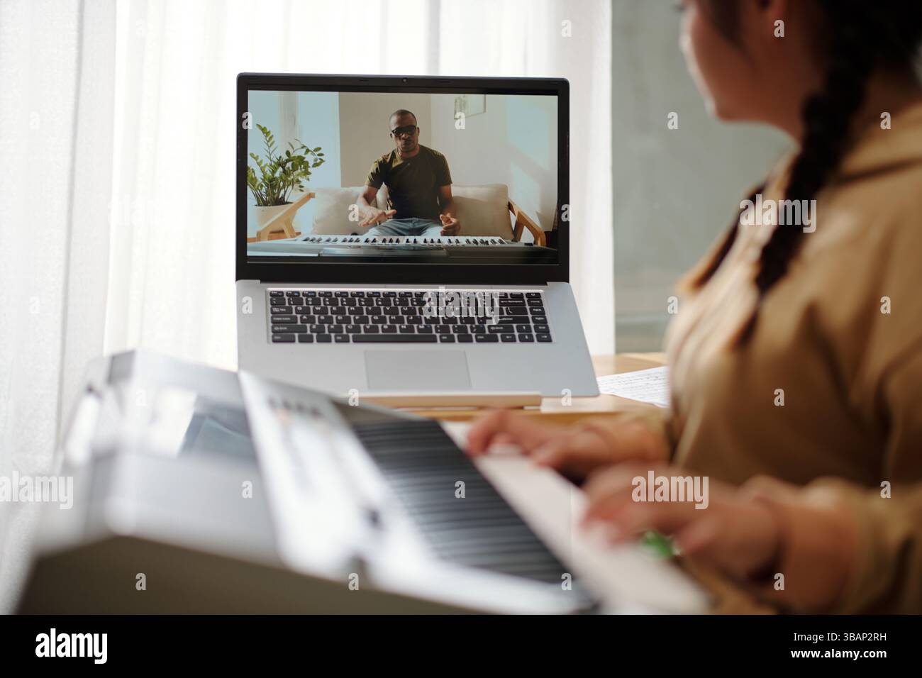 Girl following tutorial on laptop screen when learning playing ...