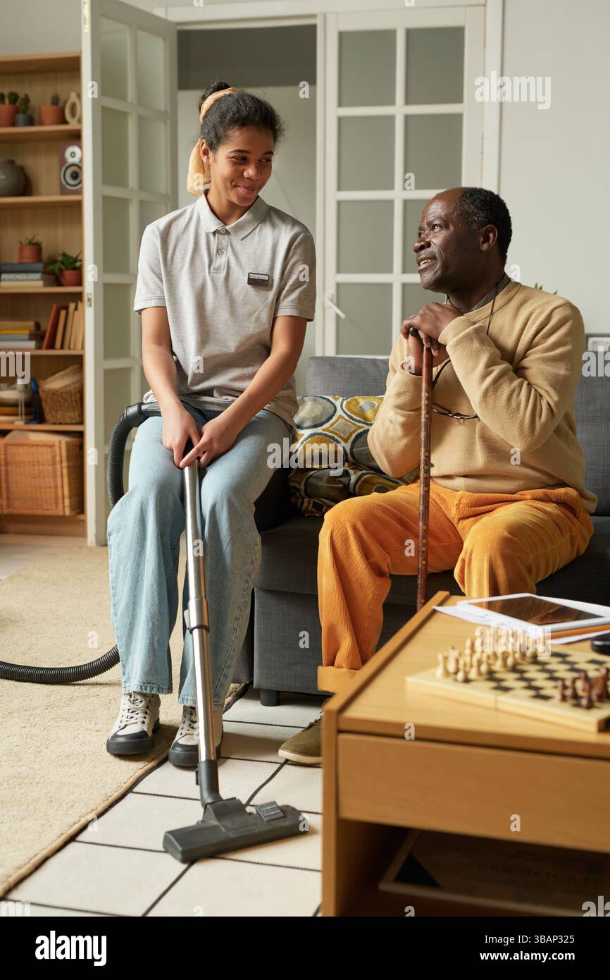 Black young female social service worker wearing uniform holding vacuum ...