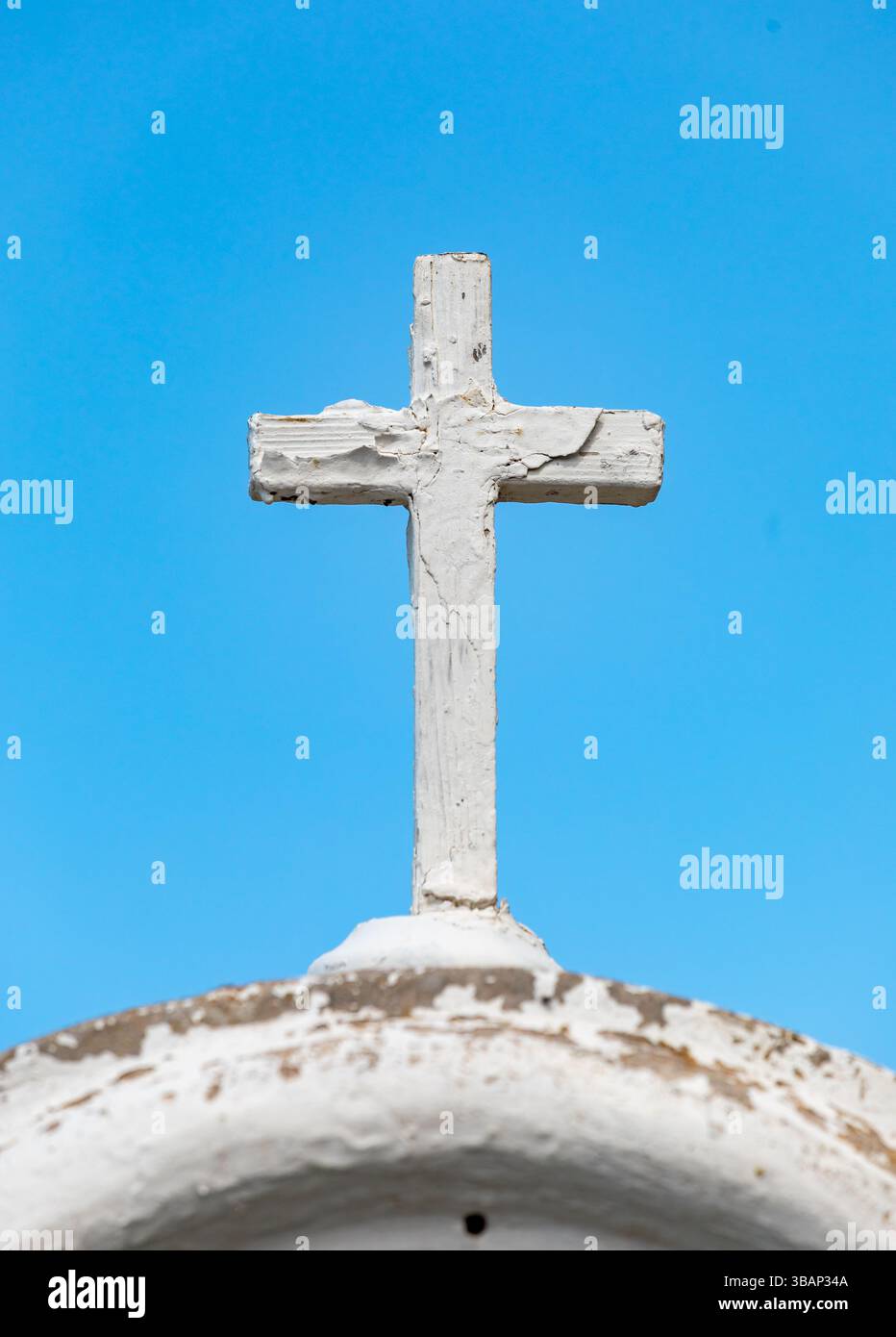 Simple white wooden cross with peeling paint standing on top of a ...