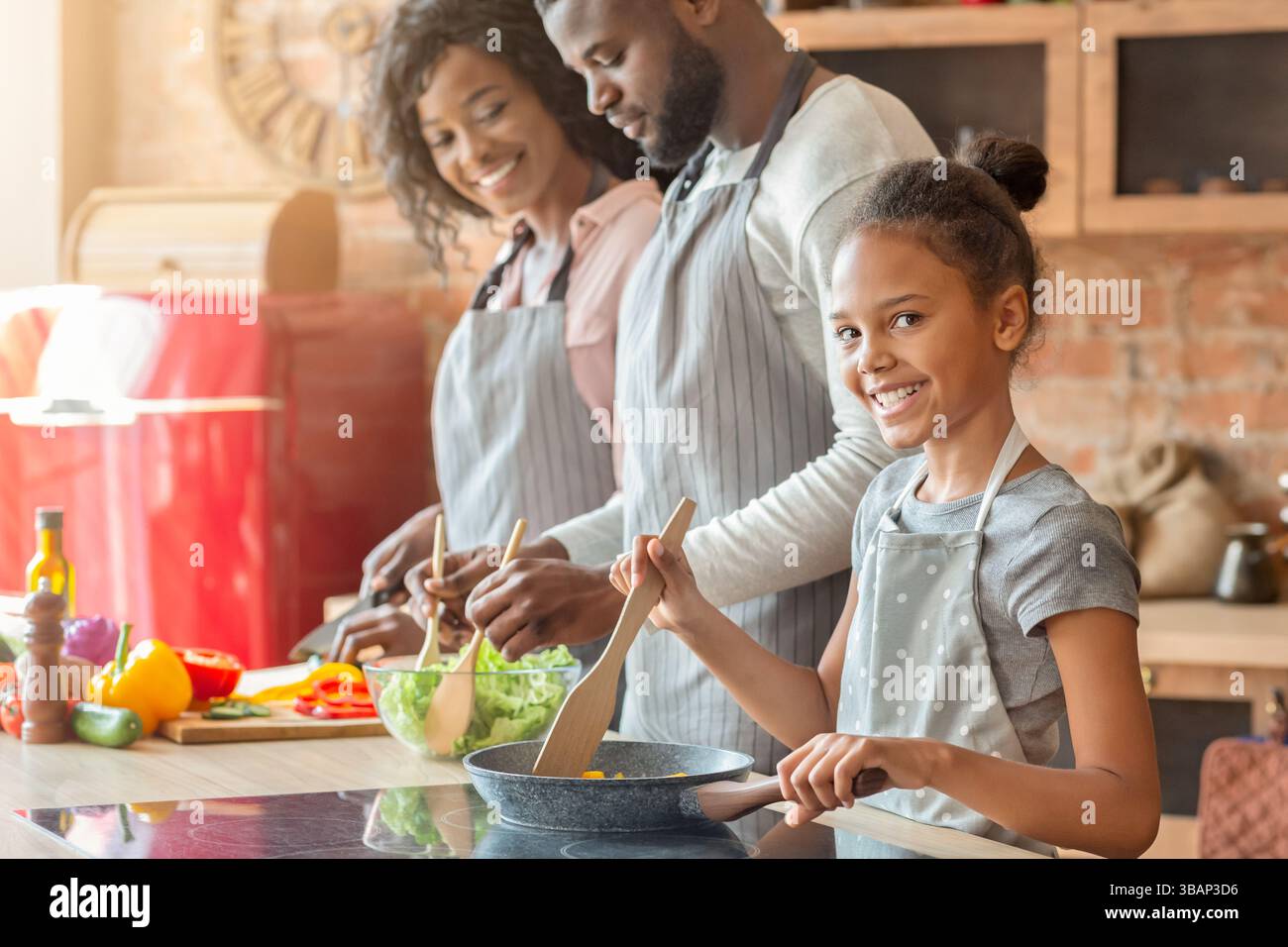 Smiling african little girl helping parents cooking healthy dinner in ...