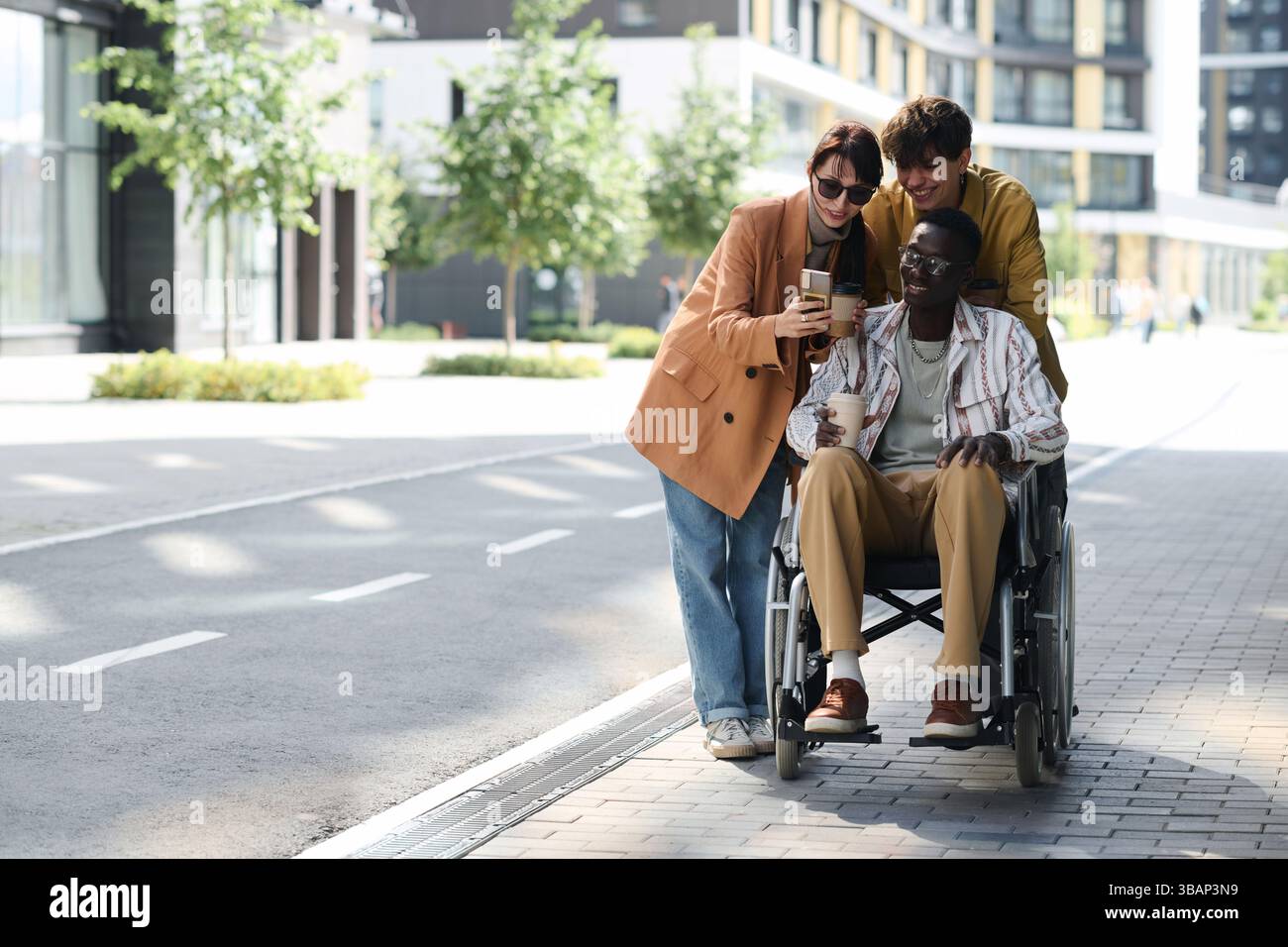 Friends showing photos on smartphone to their friend with disability ...