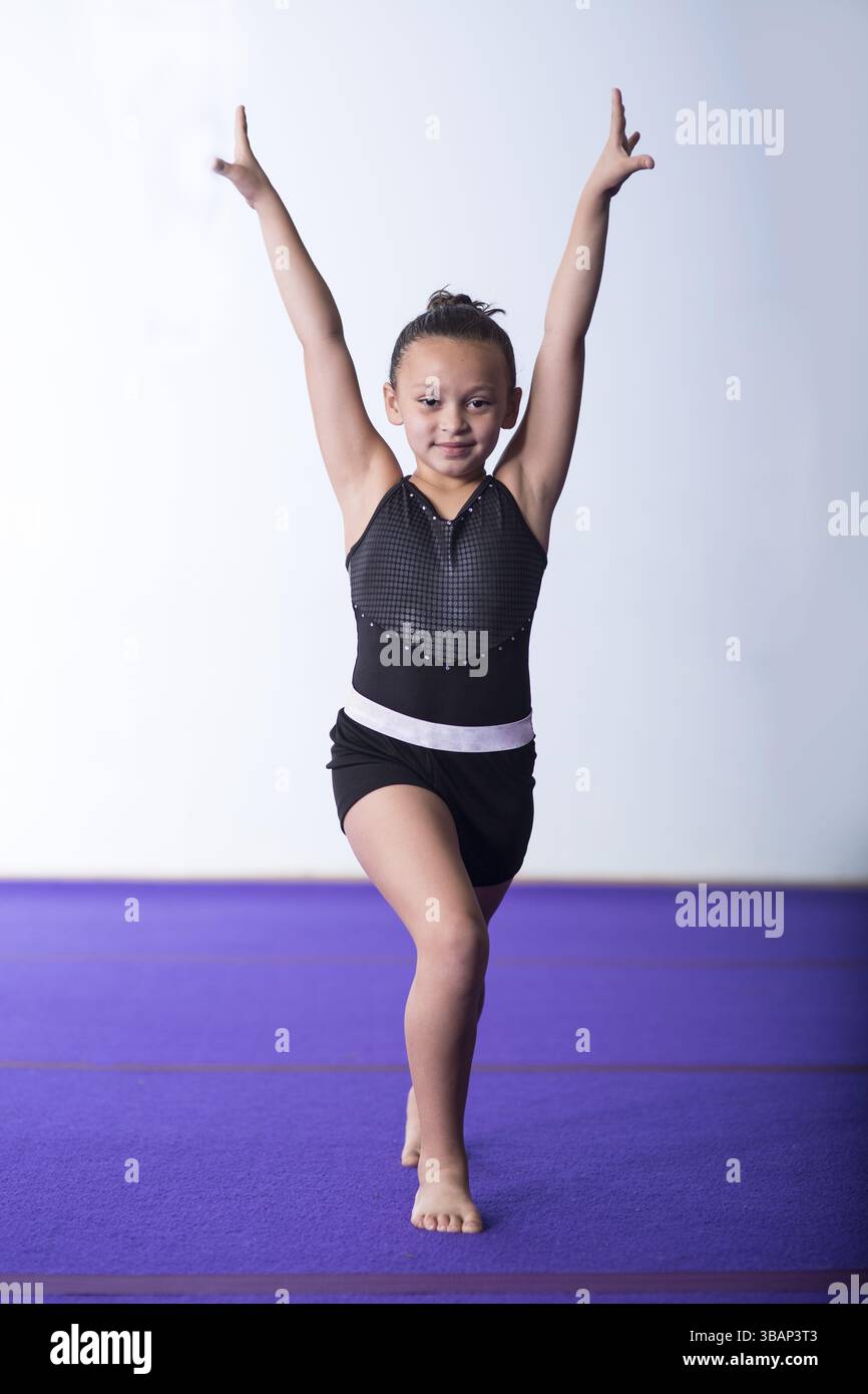 Young Latina girl gymnast smiling standing one foot forward both hands ...