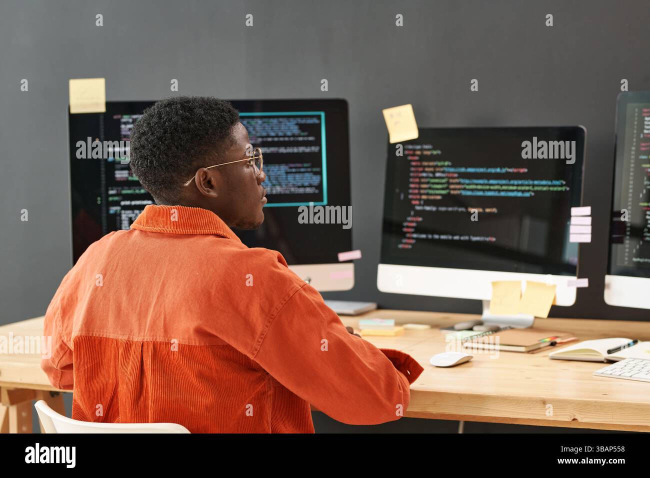 Rear view of young black man concentrating on decoding data on computer ...