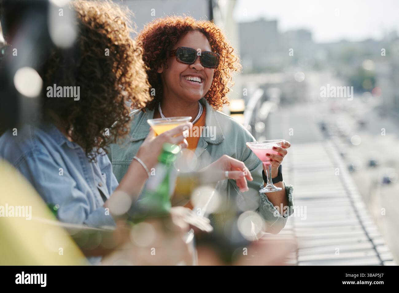 Young cheerful black woman with cocktail enjoying gathering with ...