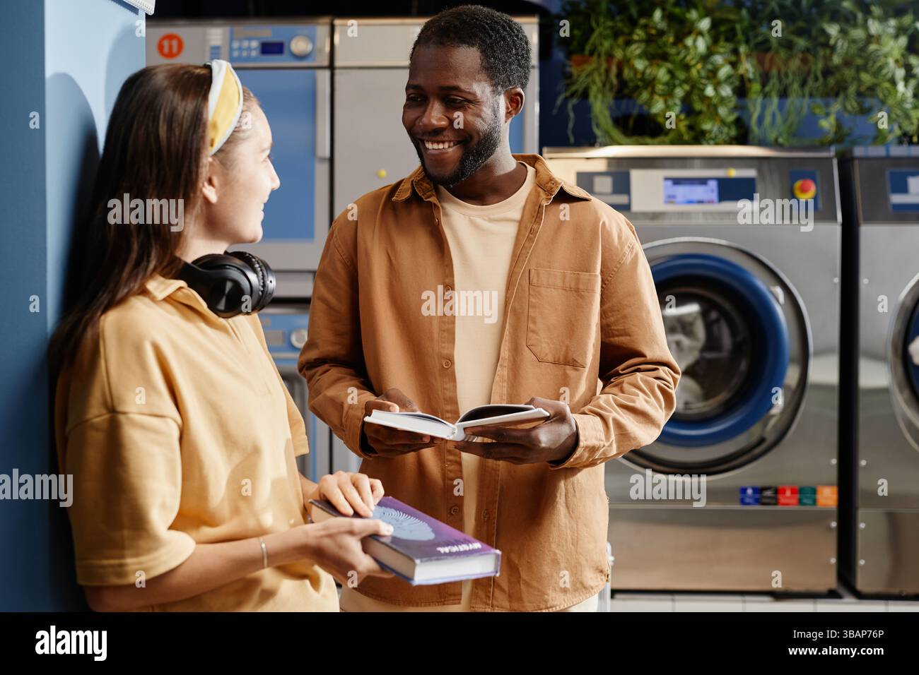 Two happy young intercultural students with books discussing their ...