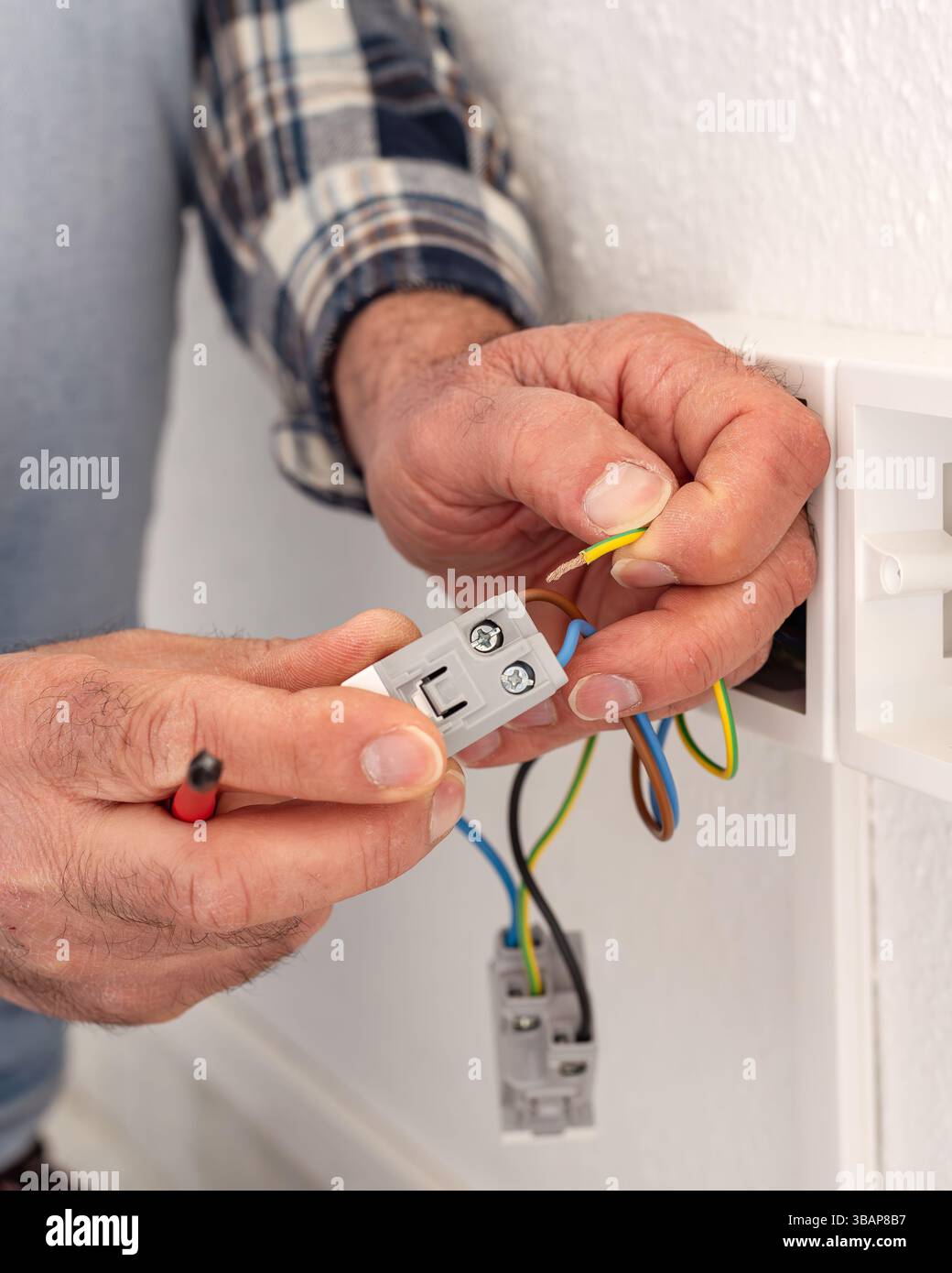 Electrician worker inserts electrical cables into the socket terminals ...