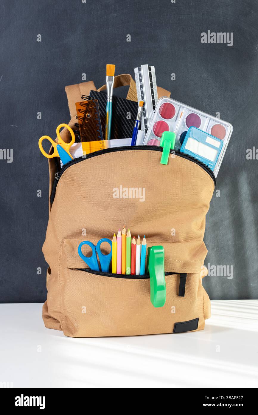 School backpack overflowing with Stationery Supplies on blackboard ...