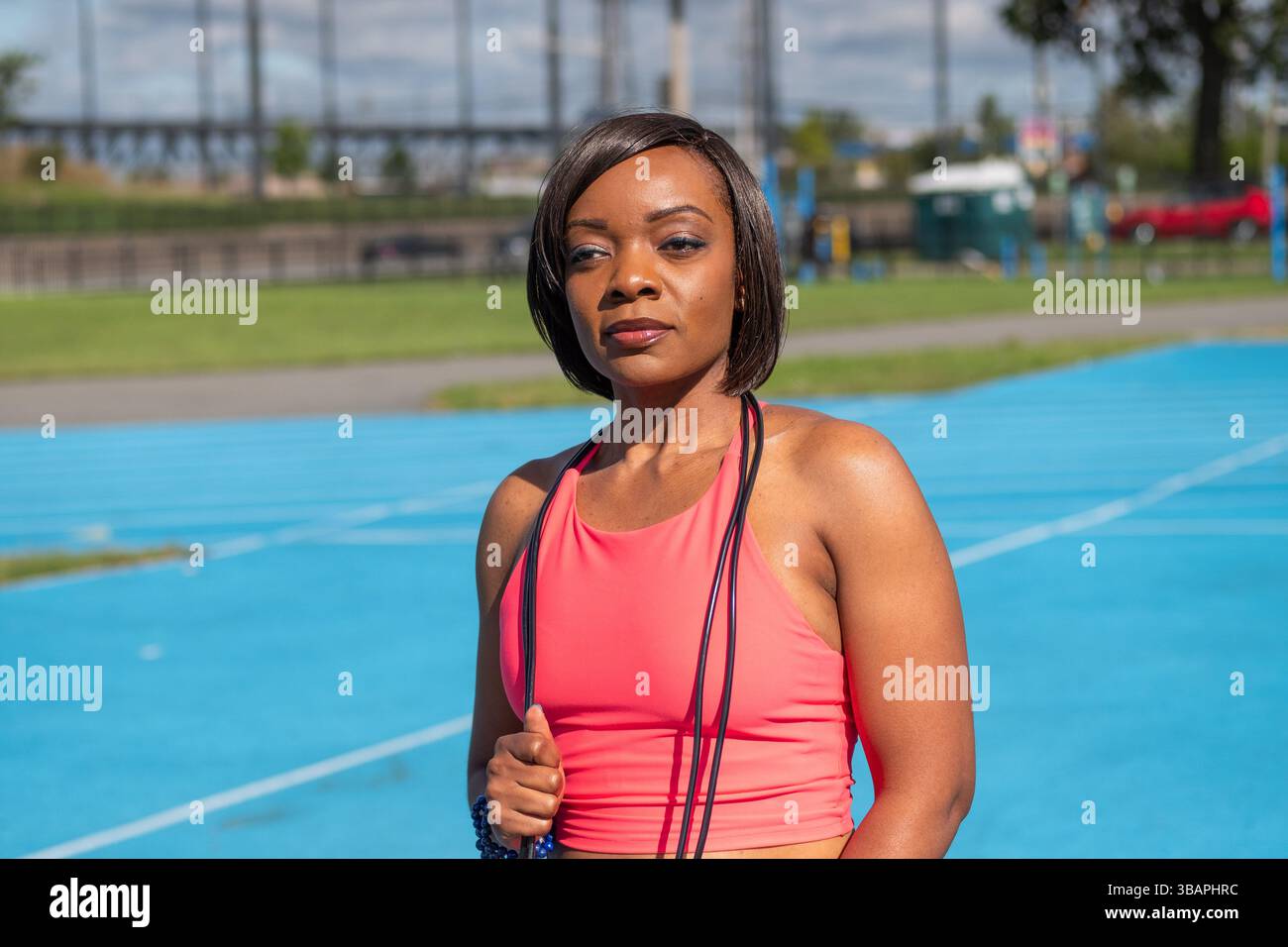 Serious Black woman in pink activewear looking away while standing with ...