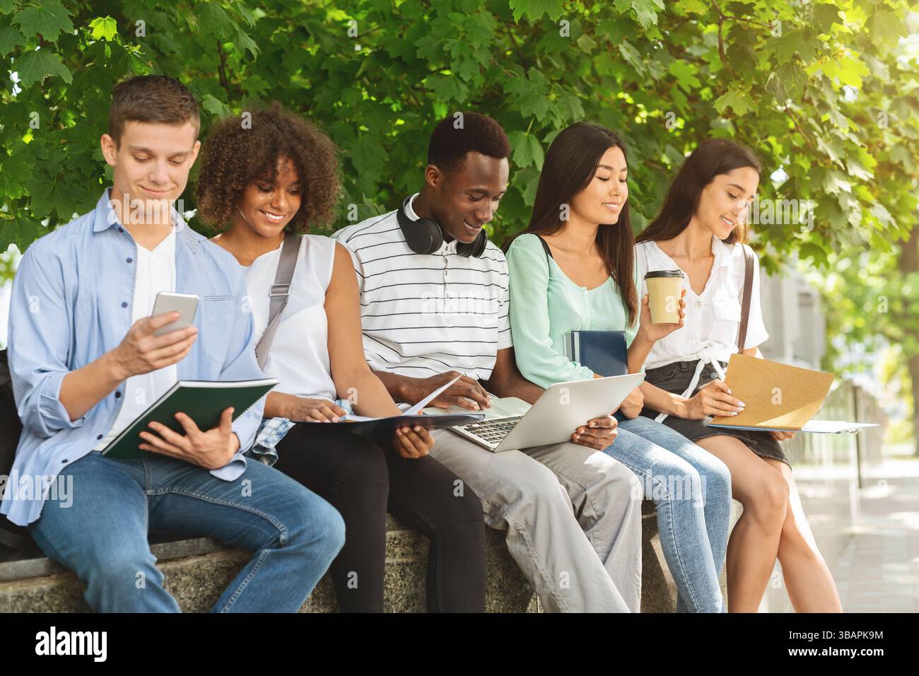 Group of students preparing for exam in park near university, having ...