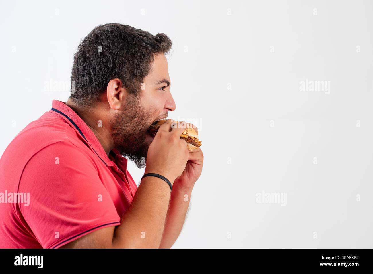Young fat man eating fast food hamburger on white background. High ...