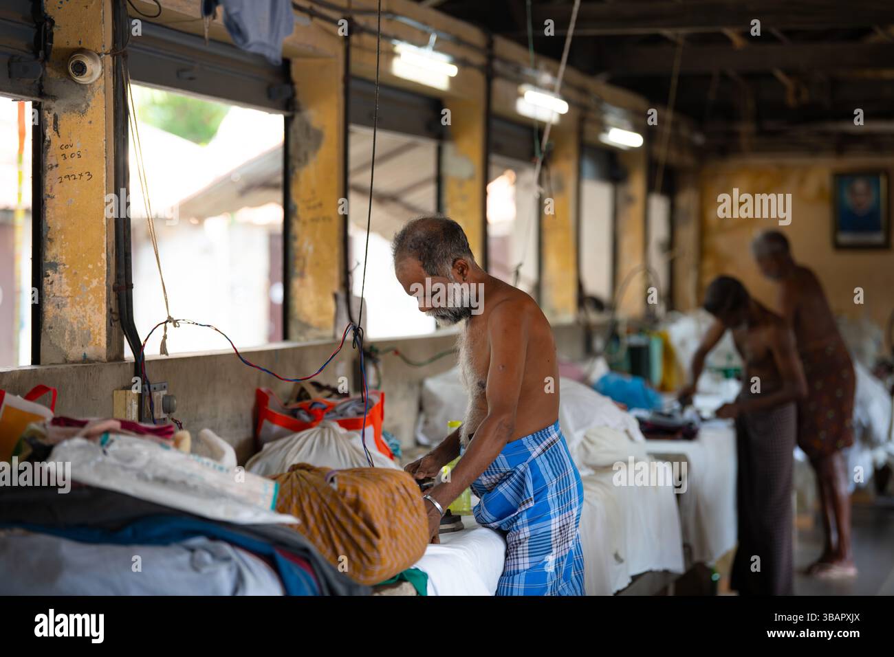 Man working with traditional indian electrical iron, Dhobi Ghat, open ...