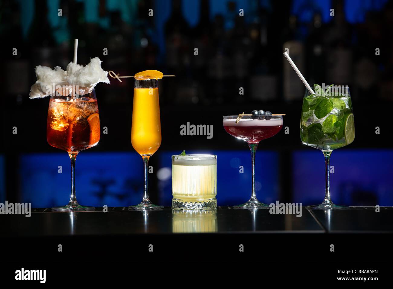 row of various colourfull alcoholic cocktails on a bar desk. Glasses of ...