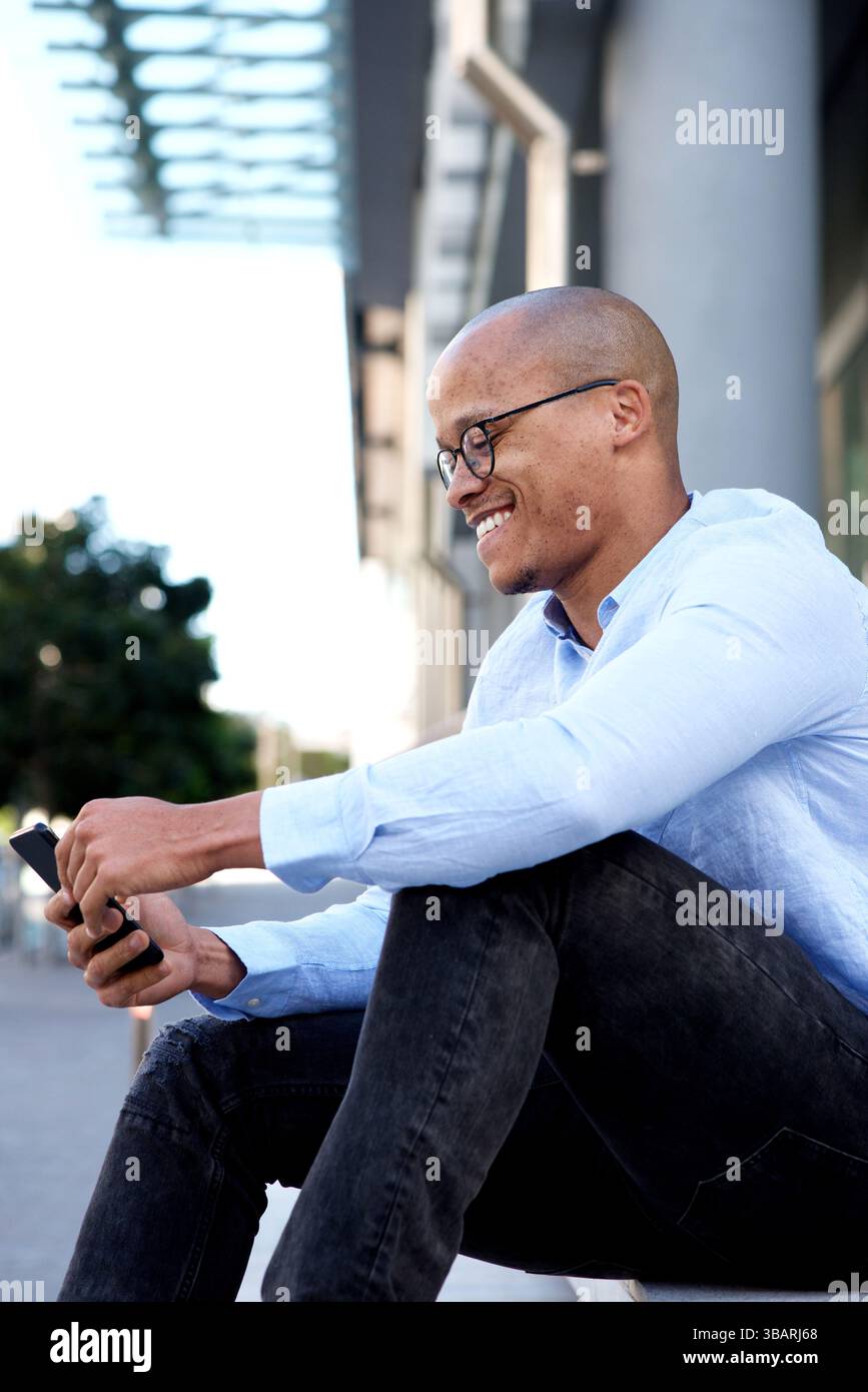 Smiling African American man browsing social media posts on phone while ...