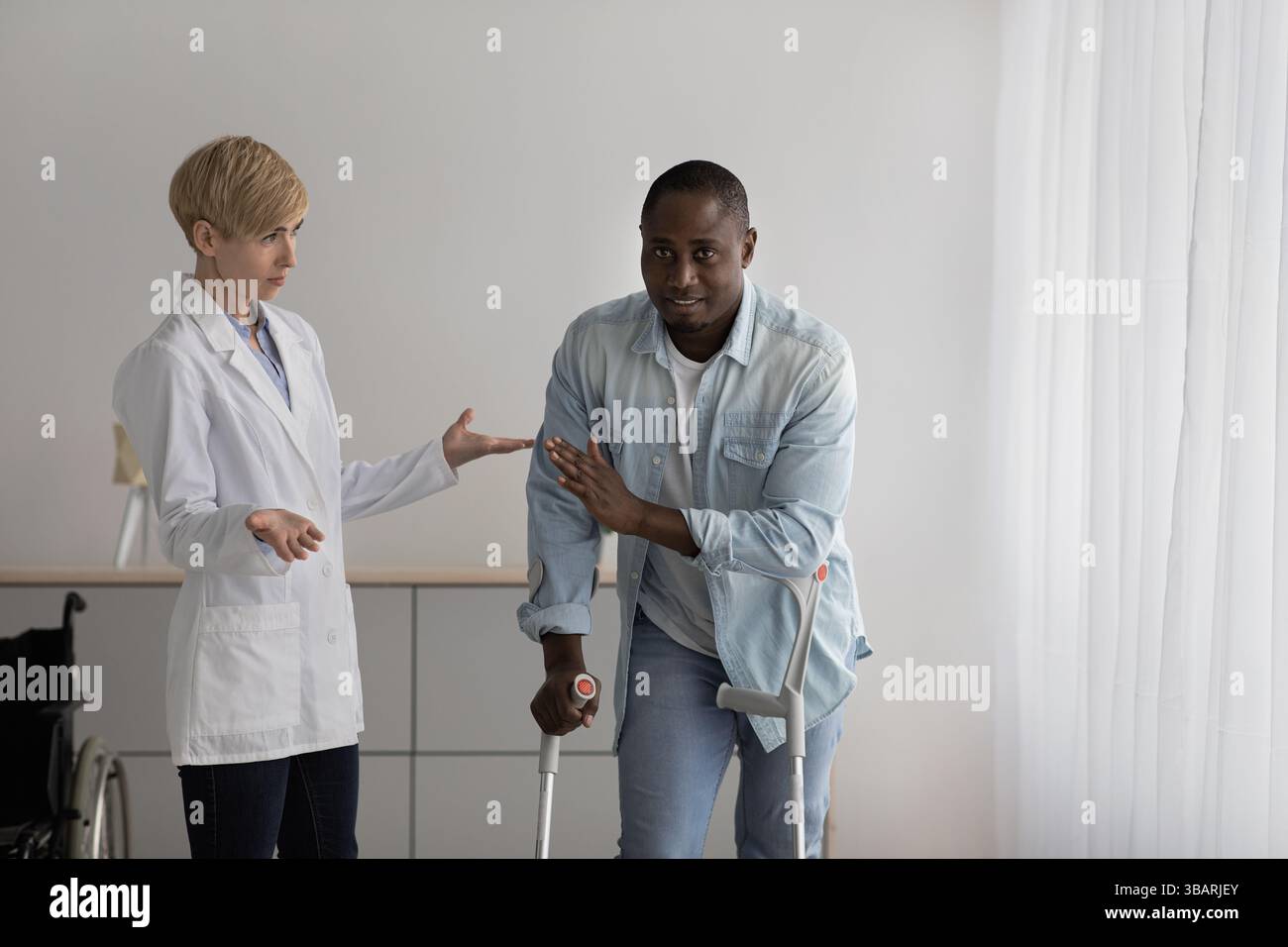 Disabled Black man standing with crutches and refusing help of ...